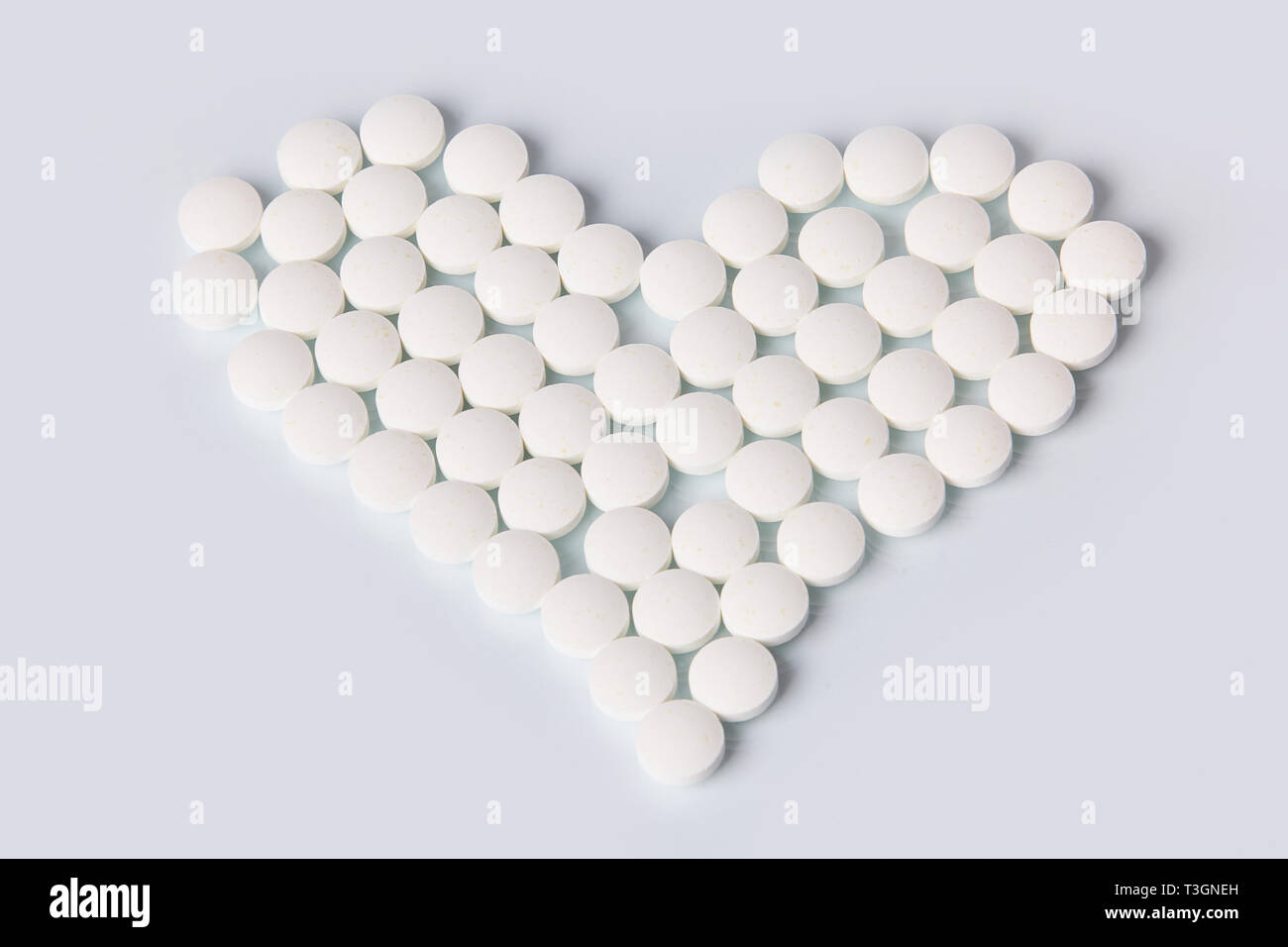 Heart made of white pills. Isolated on white background. Space for text ...