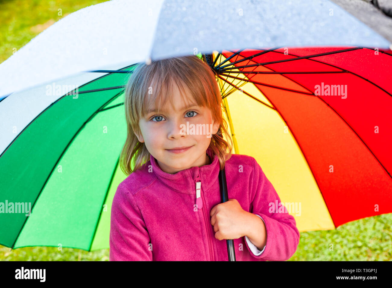 Portrait of jittle girl wearing fleece jacket standing hiding under ...