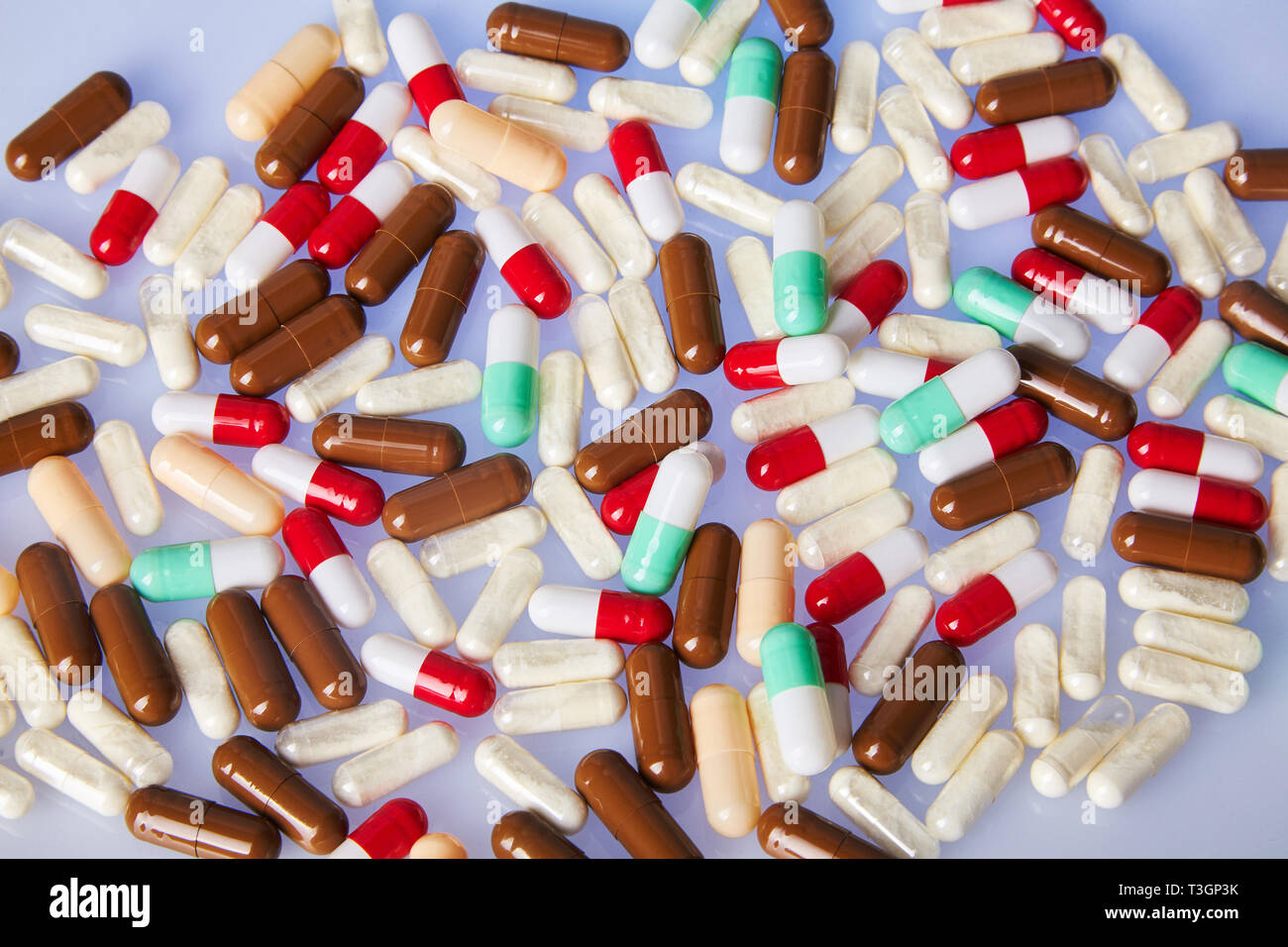 Lots of colorful drugs and pills on blue mirror background. Scattered ...