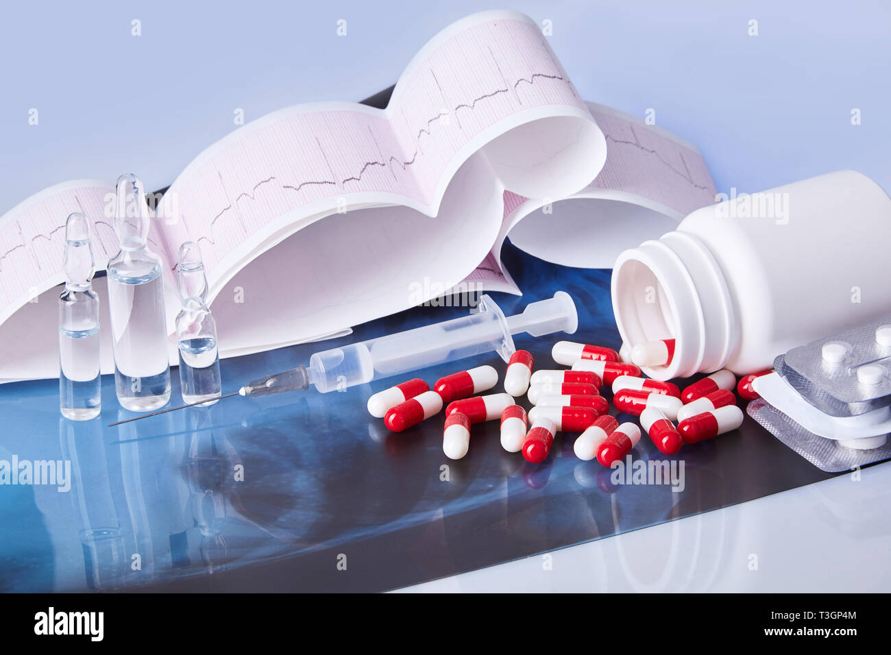 Scattered capsules, tablets, ampules and syringe on the table with ...