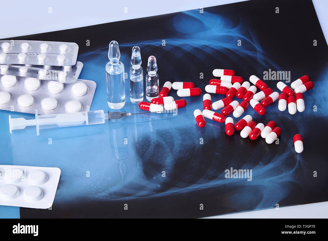 Scattered capsules, tablets, ampules and syringe on the table with ...