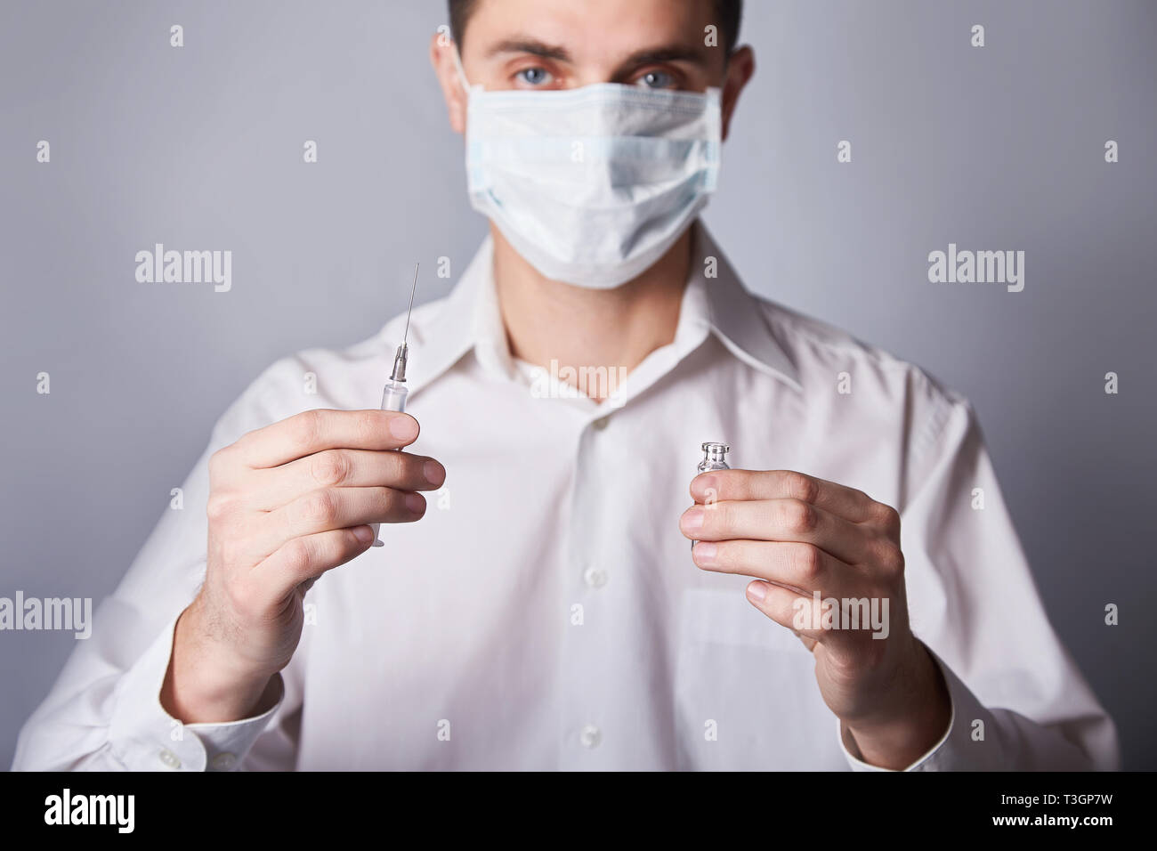 Doctor in mask with a injection syringe on the blue background Stock ...