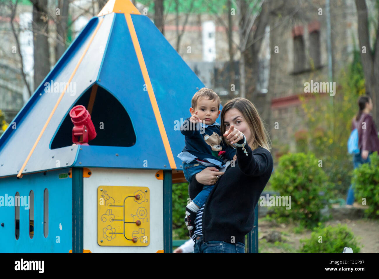 Baby boy pointing at the camera. Mother and son standing on outdoor ...