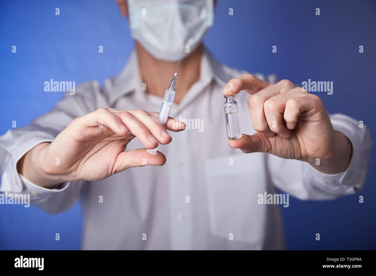 Doctor in mask with a injection syringe on the blue background Stock ...