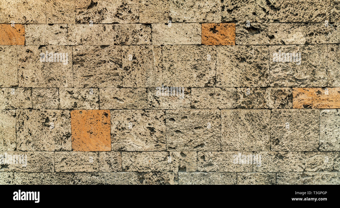 Polished limestone wall. Building facade decorated with tiles made of ...