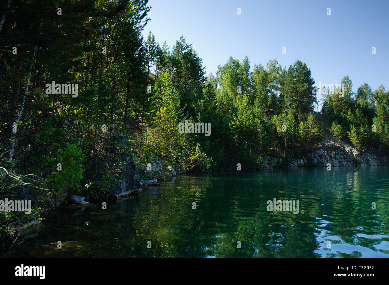 mountain lake in the summer at noon with vacationers and swimming ...