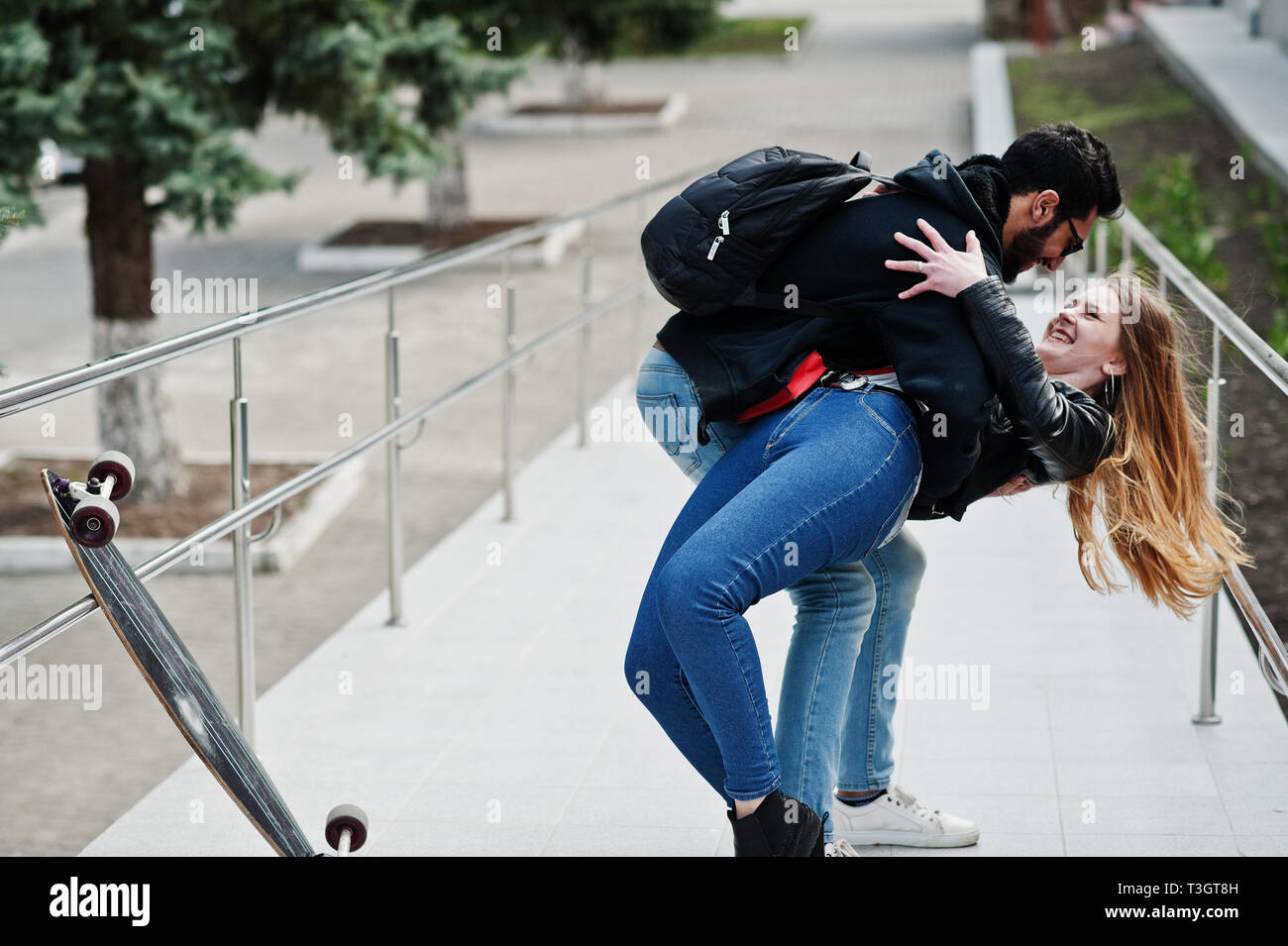 Cool multiracial couple posing with longboard and hugs together Stock ...