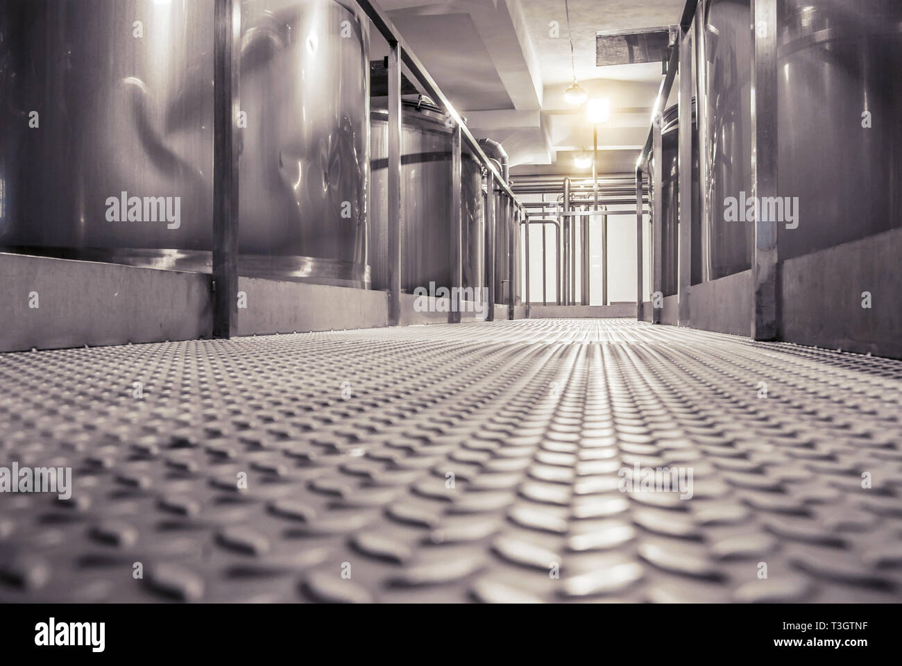 Metal floor in the factory between large metal barrels Stock Photo - Alamy
