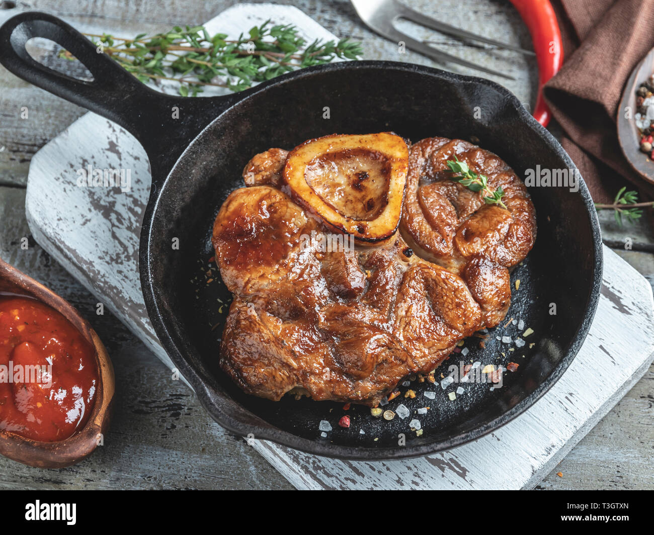 Osso buco cooked veal shank on a portion iron pan, red sauce, spices ...