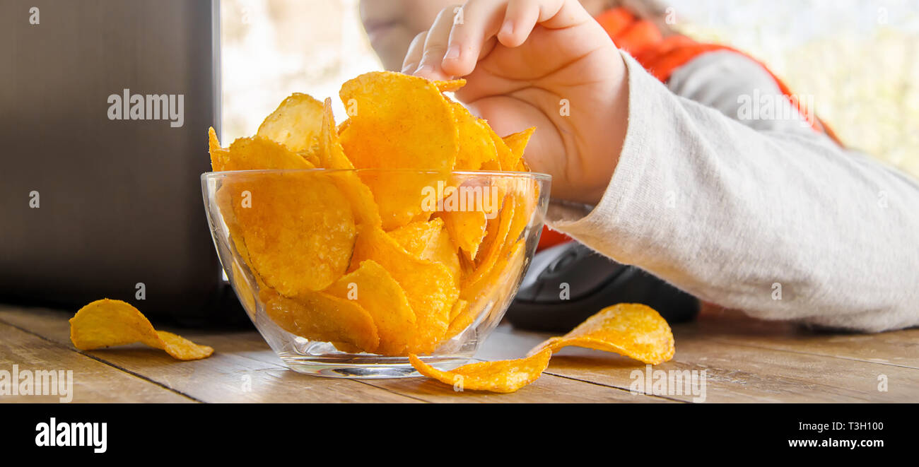 child with chips behind a computer. selective focus. food Stock Photo ...
