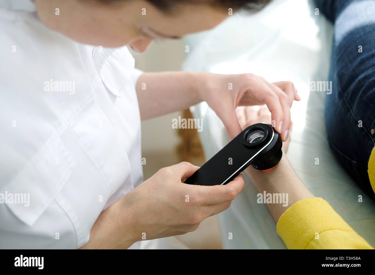 Female dermatologist using a professional dermatoscope while doing skin ...
