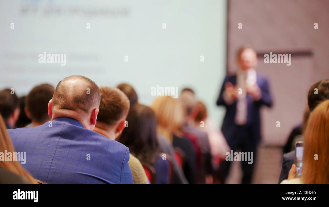A business presentation. People sitting on the chairs and looking at ...