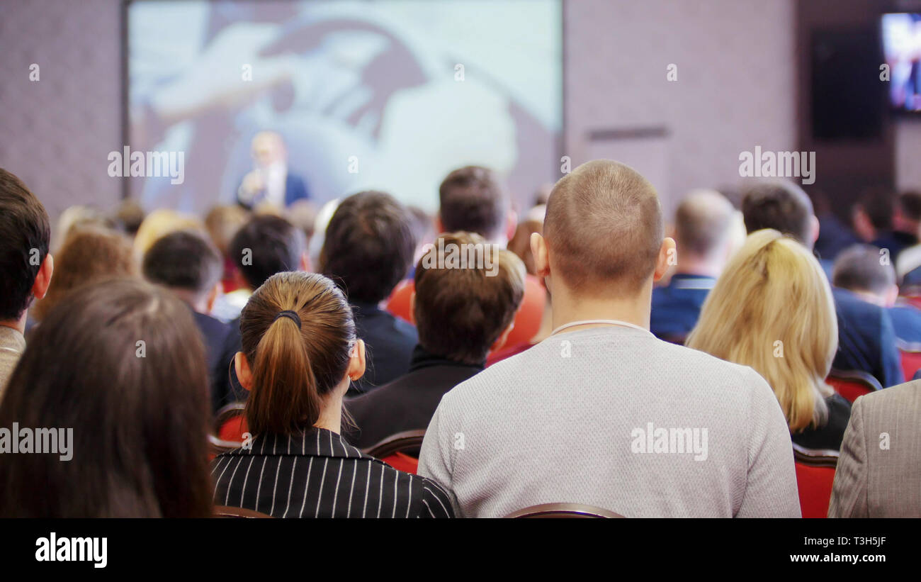 A business conference. People sitting on the chairs and watching the ...