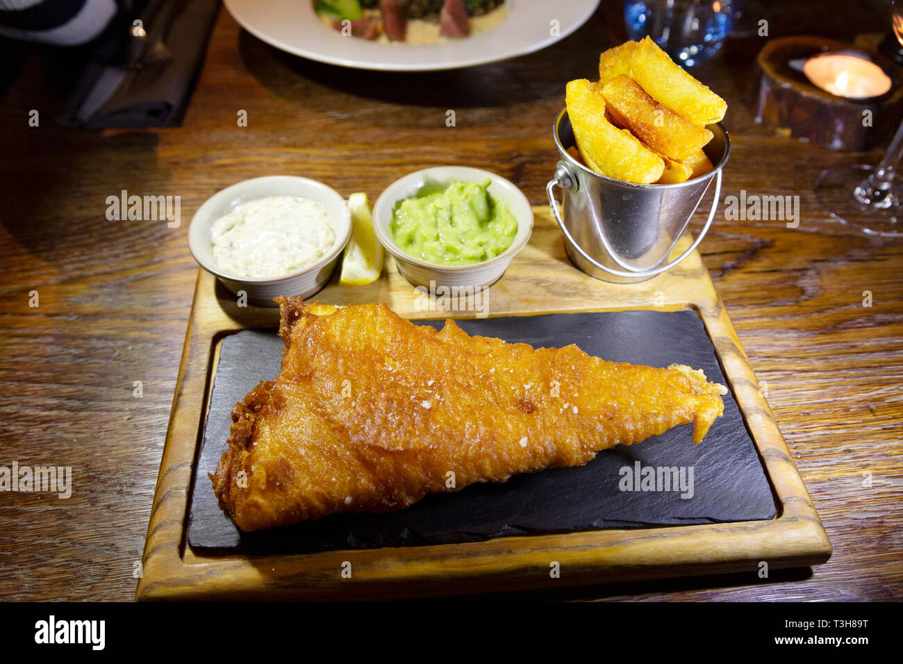 Fish and chips served with tartare sauce and mushy peas. The beer ...
