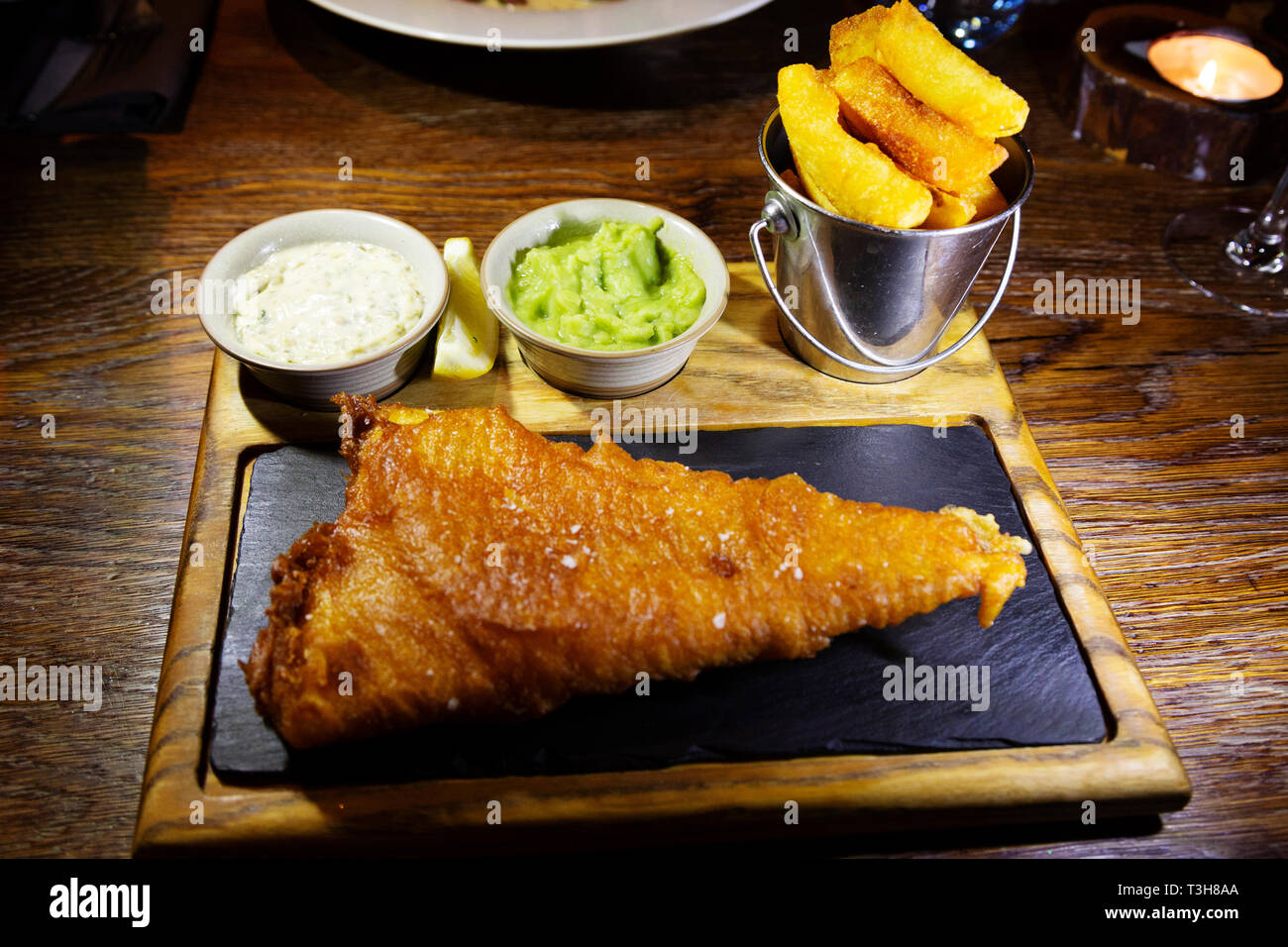 Fish and chips served with tartare sauce and mushy peas. The beer ...