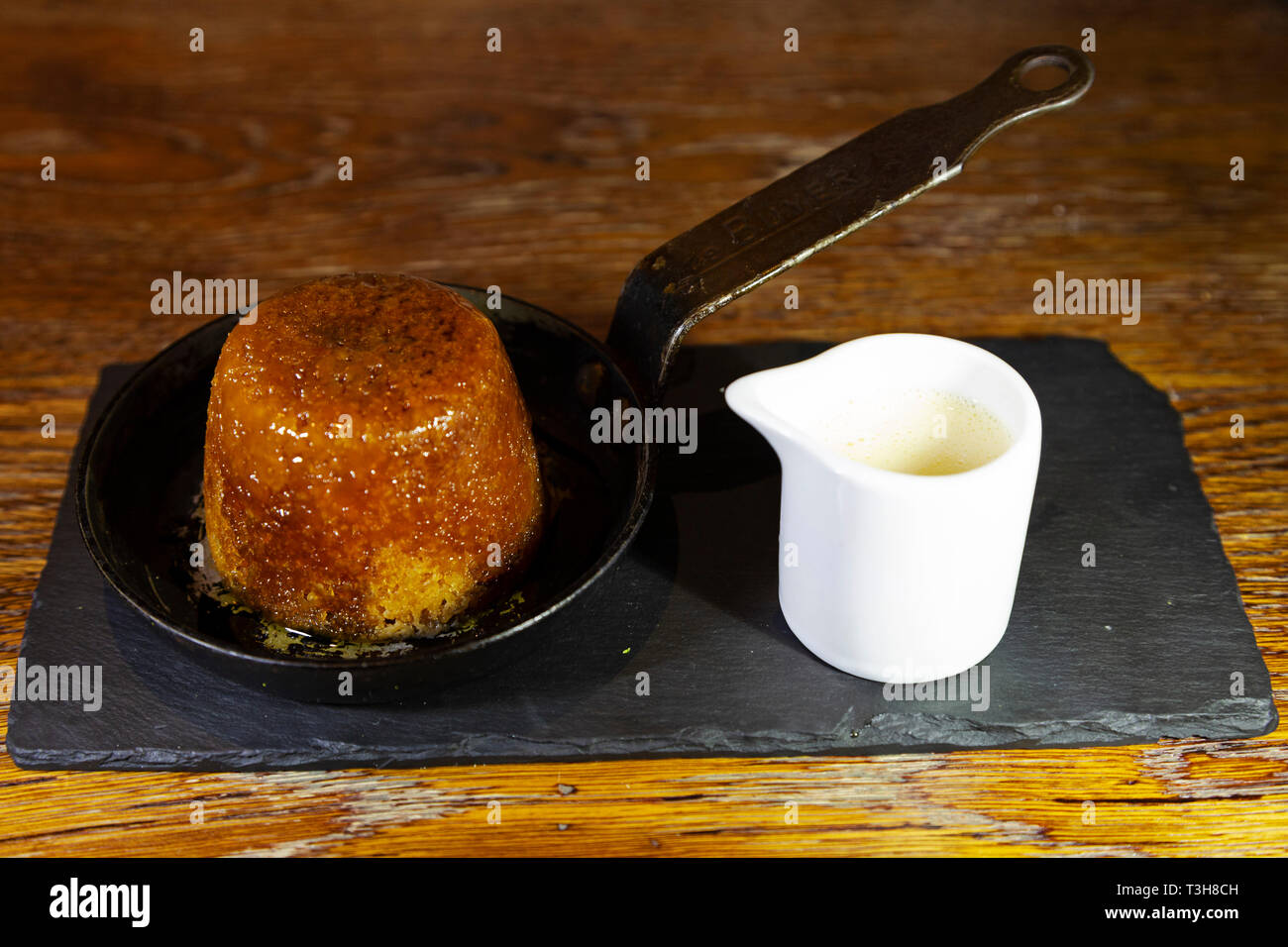 Sticky toffee pudding served with caramel sauce and a jug of custard ...