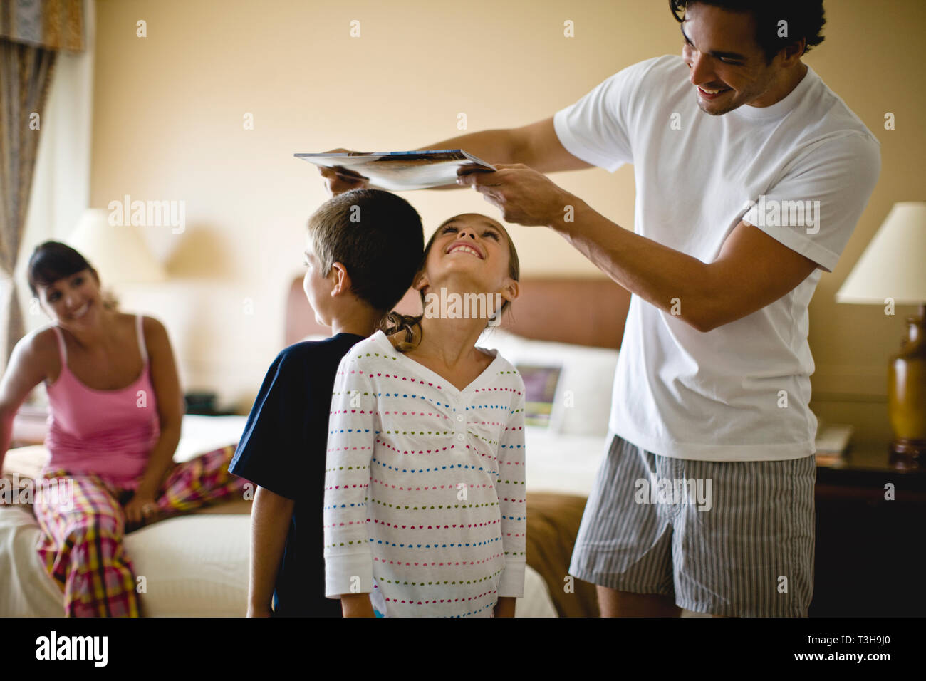 Father comparing the heights of his two children Stock Photo - Alamy