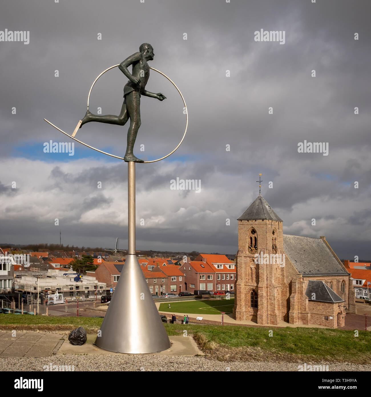 Old church of Zoutelande with statue of an athlete running a marathon ...