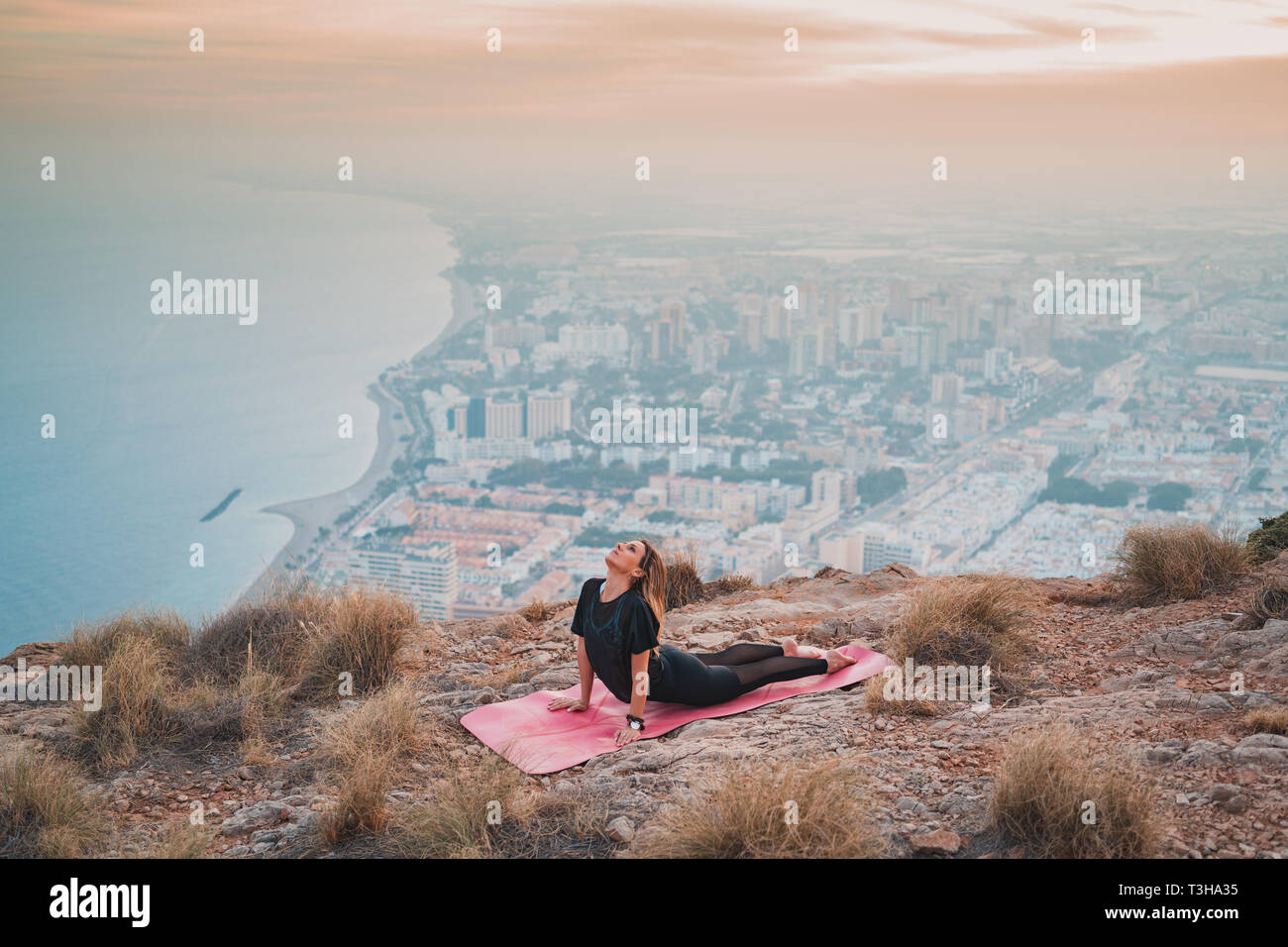 Beautiful young woman doing yoga at the top of the mountain with views ...