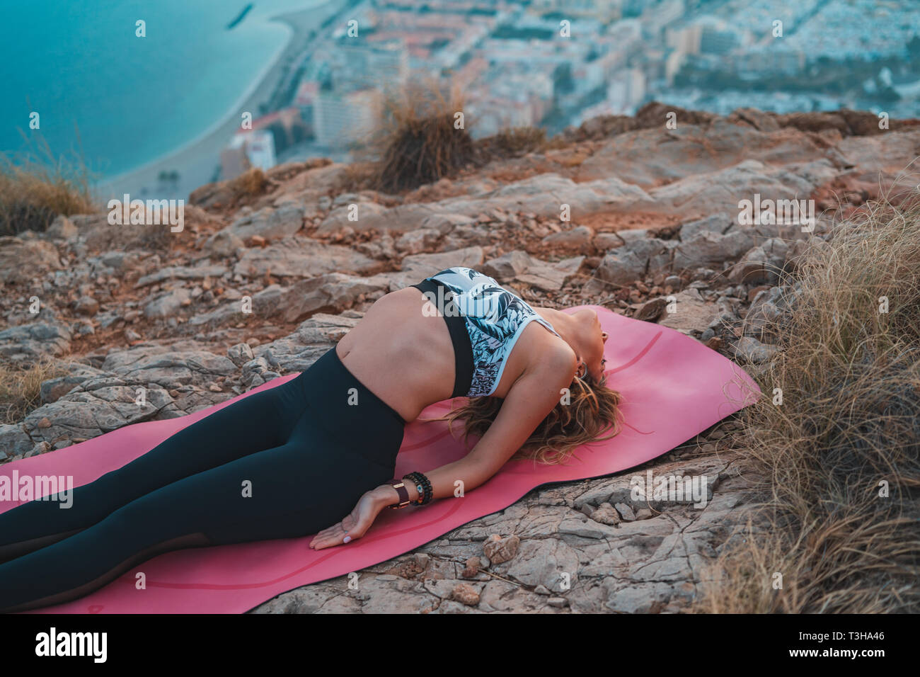 Beautiful young woman doing yoga at the top of the mountain with views ...