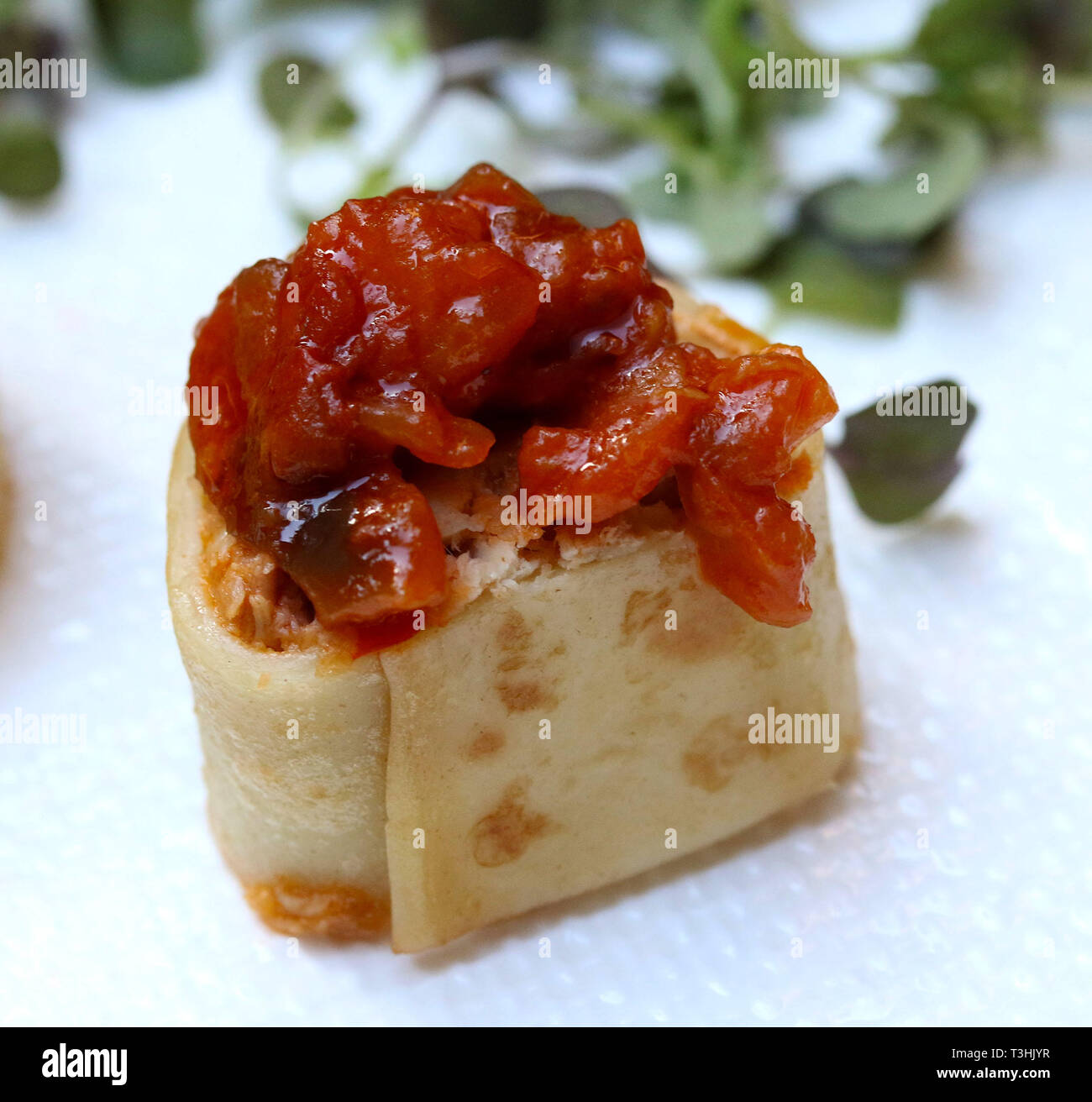 Chicken wrap appetizers covered with tomato, roasted pepper and herbs ...