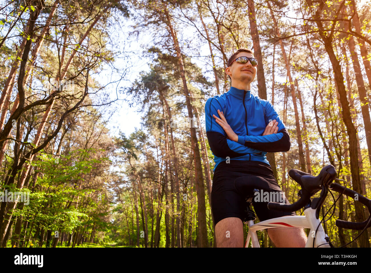 Young man bicyclist riding a road bike in spring forest in the morning ...