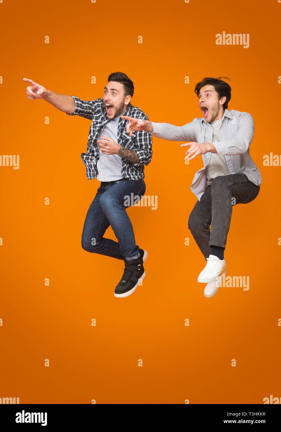 Two excited men pointing fingers away, jumping over background Stock ...