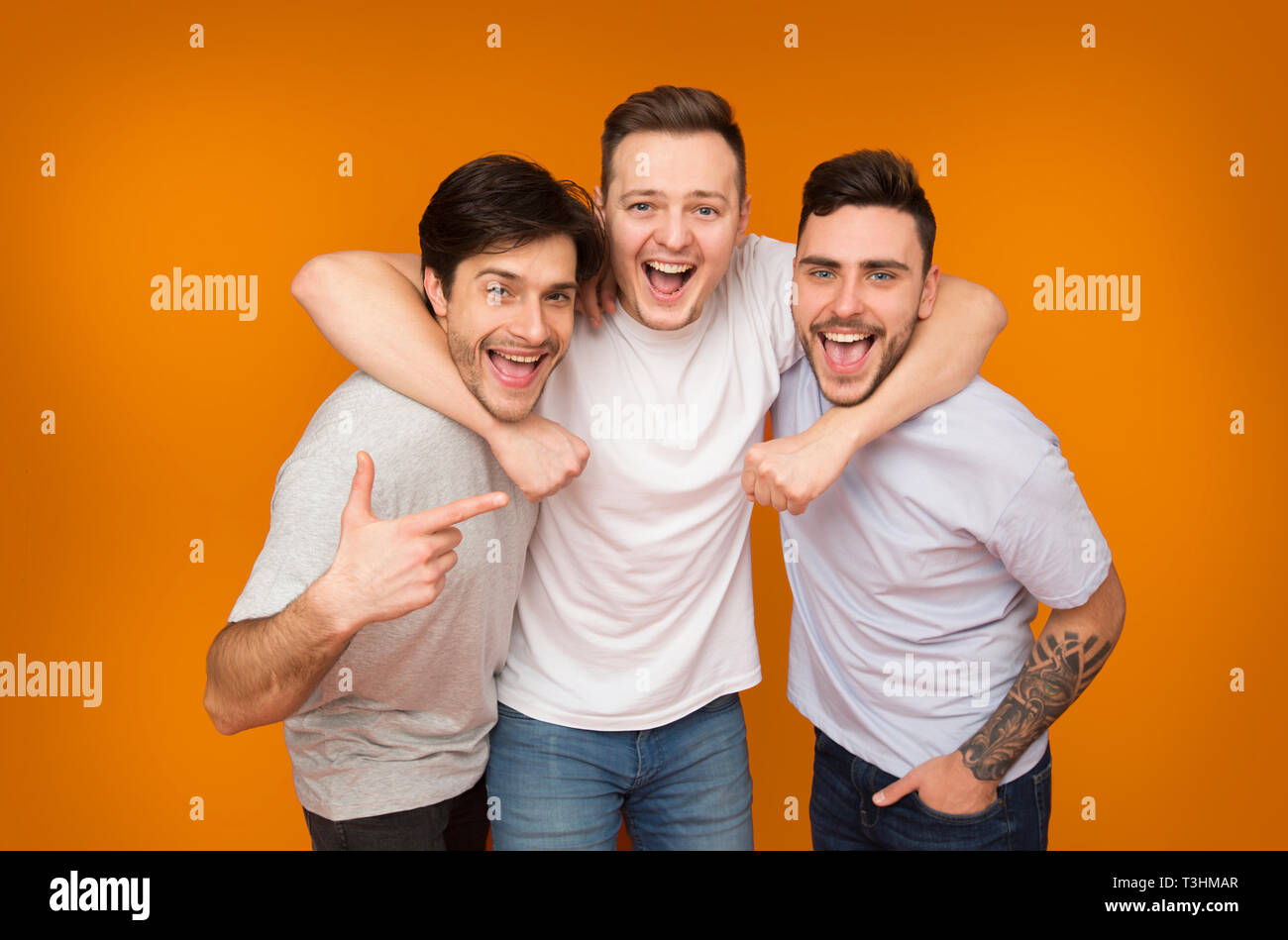 Best friends. Men posing over orange background Stock Photo - Alamy