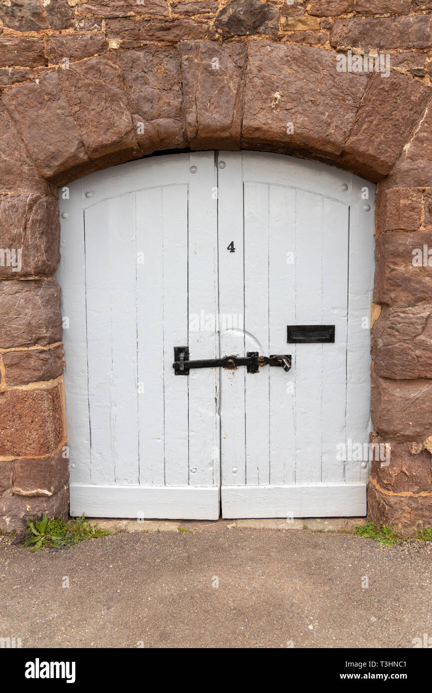 White wooden door with number 4 and large black lock in stone wall ...