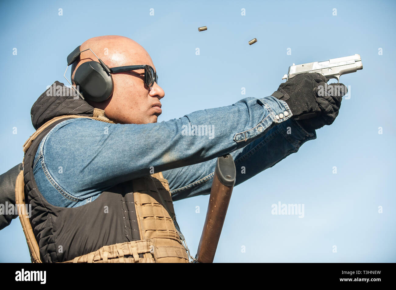 Detail view of shooter holding gun in hand and shooting, close up ...