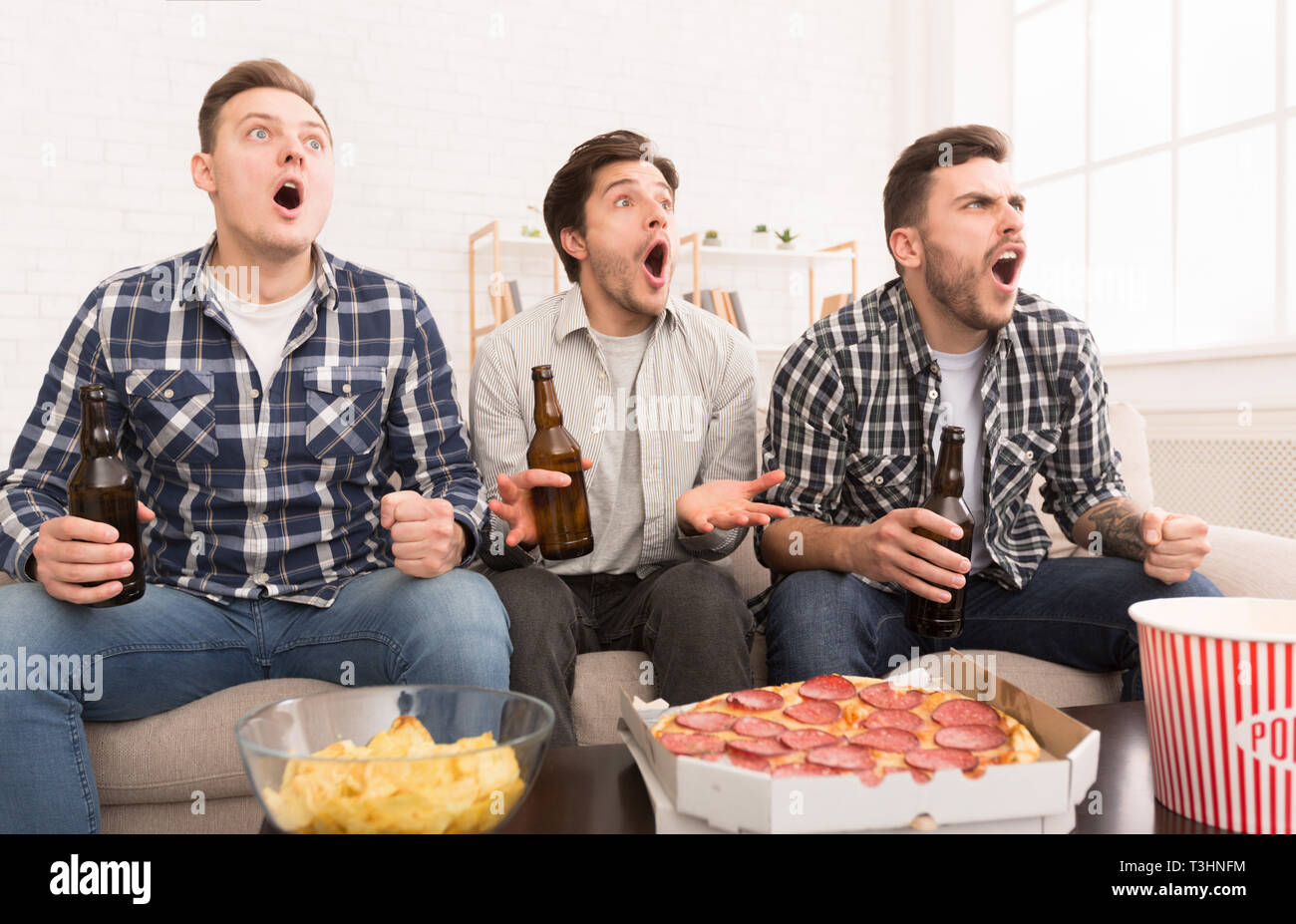 Lost match. Shocked friends watching football game Stock Photo - Alamy