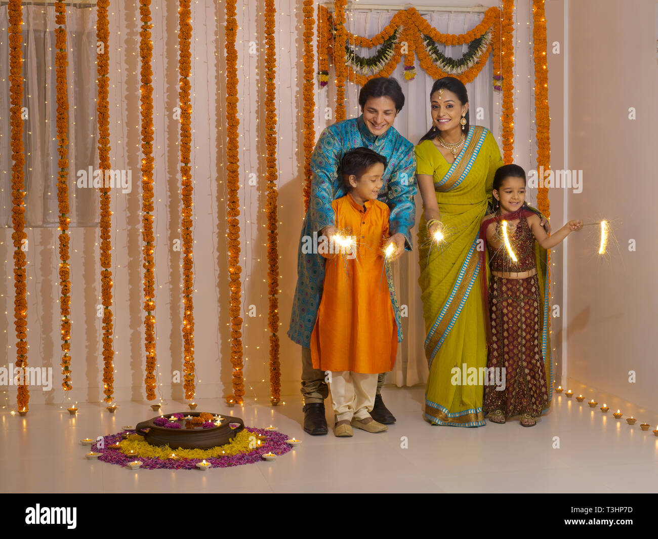 PORTRAIT OF AN INDIAN FAMILY OF FOUR CELEBRATING THE FESTIVAL OF DIWALI ...