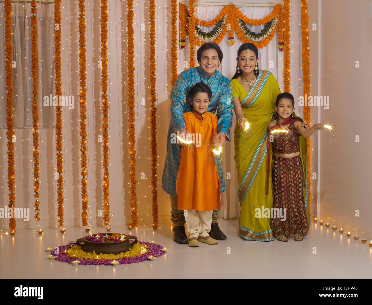 PORTRAIT OF AN INDIAN FAMILY OF FOUR CELEBRATING THE FESTIVAL OF DIWALI ...