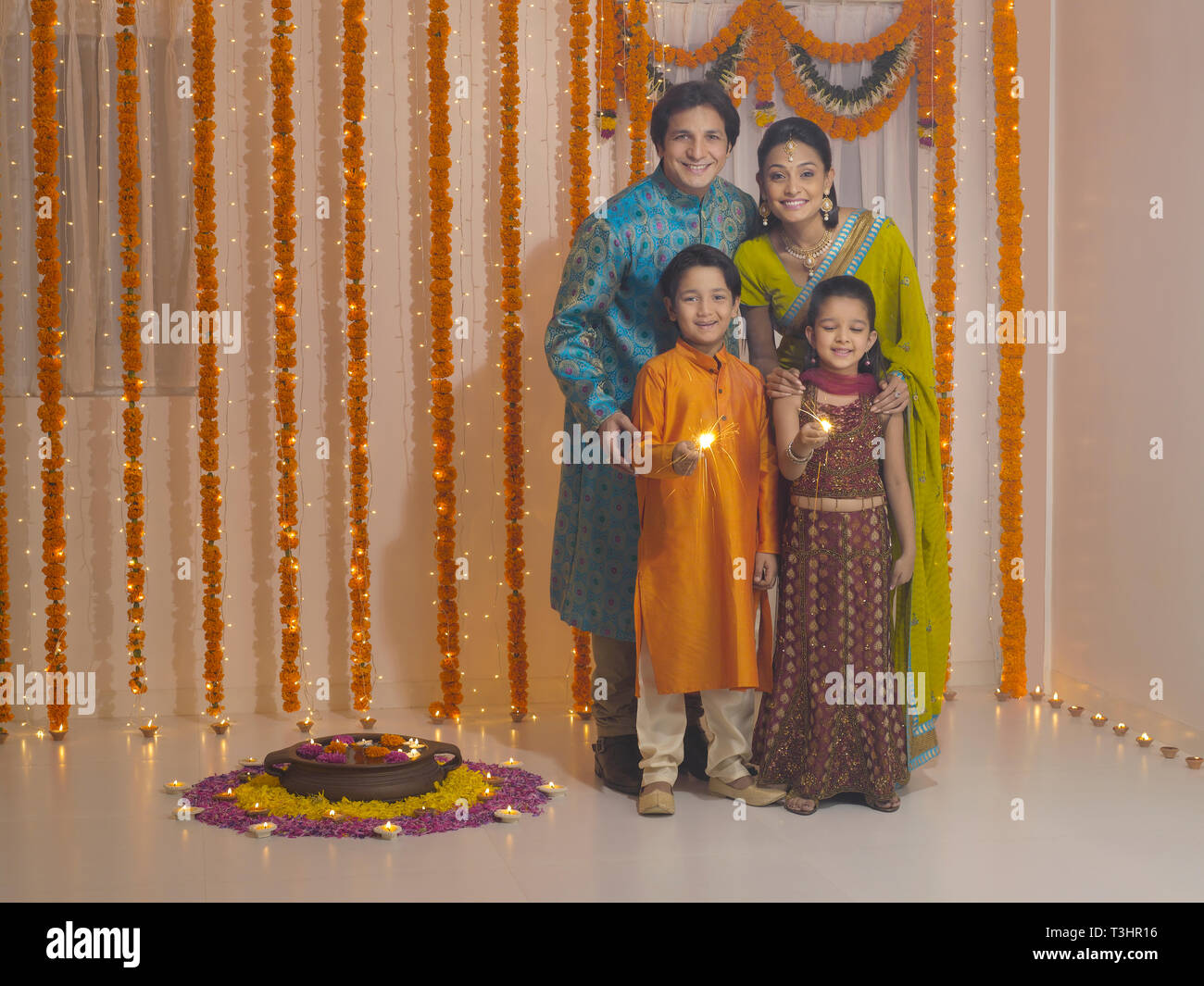 PORTRAIT OF AN INDIAN FAMILY OF FOUR CELEBRATING THE FESTIVAL OF DIWALI ...