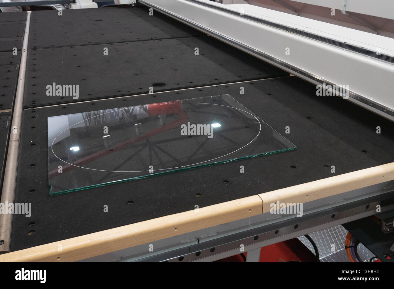 piece of transparent glass lays on industrial CNC computer remote ...