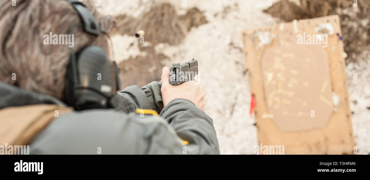 Detail back view of shooter holding gun in hand and shooting on target ...