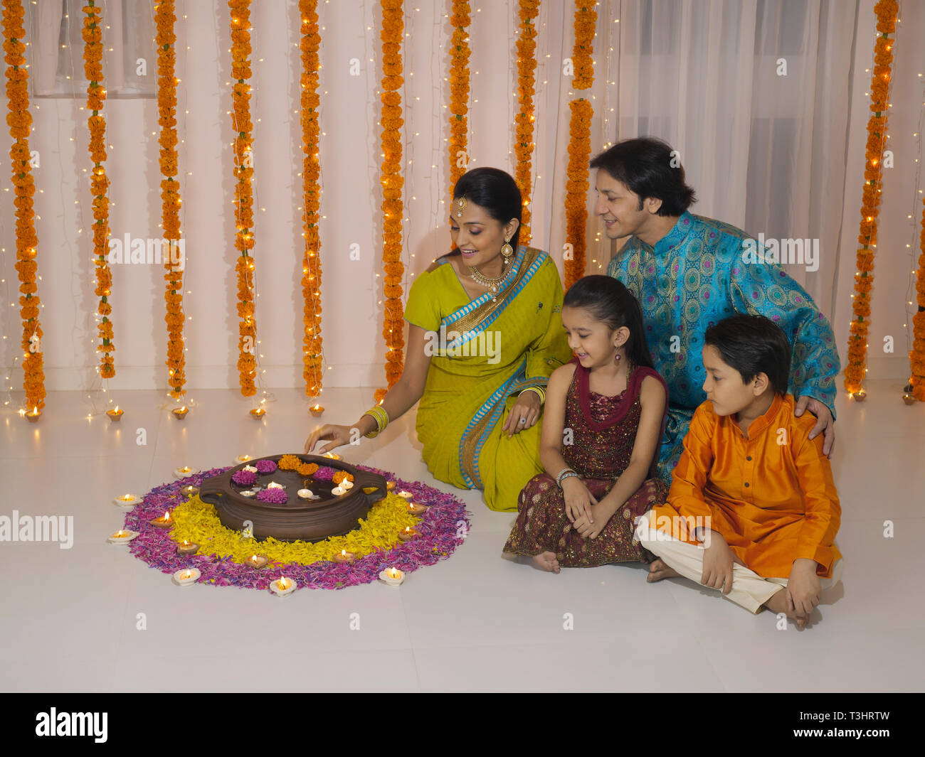 PORTRAIT OF AN INDIAN FAMILY OF FOUR CELEBRATING THE FESTIVAL OF DIWALI ...