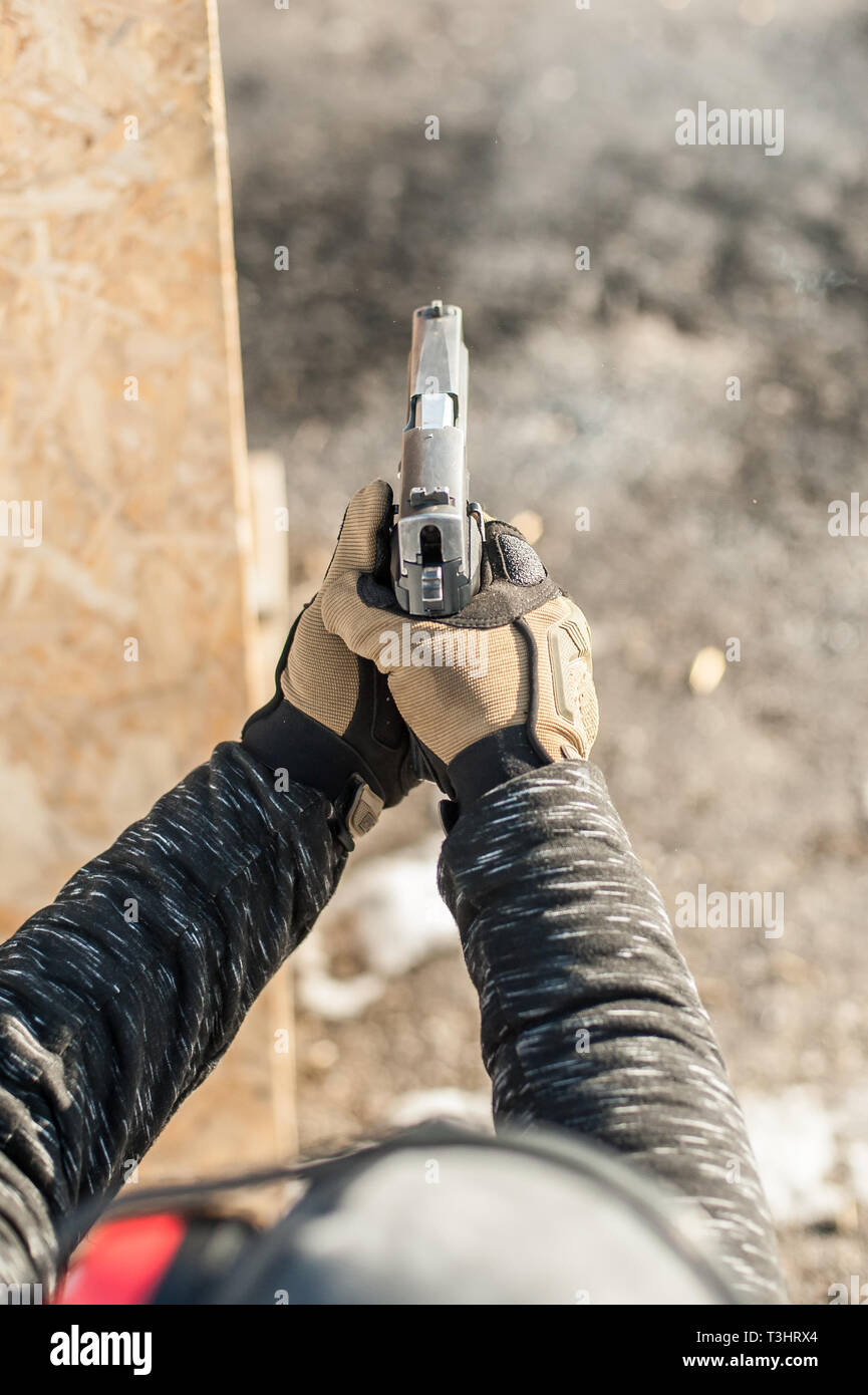 Detail back view of shooter holding gun in hand and shooting on target ...