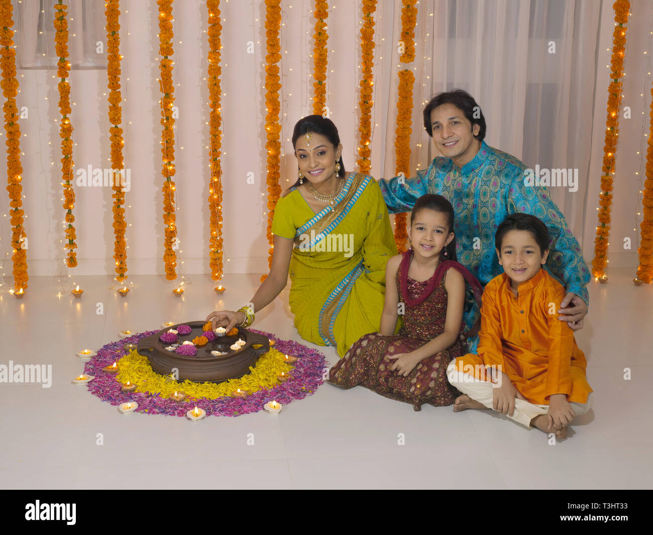 PORTRAIT OF AN INDIAN FAMILY OF FOUR CELEBRATING THE FESTIVAL OF DIWALI ...