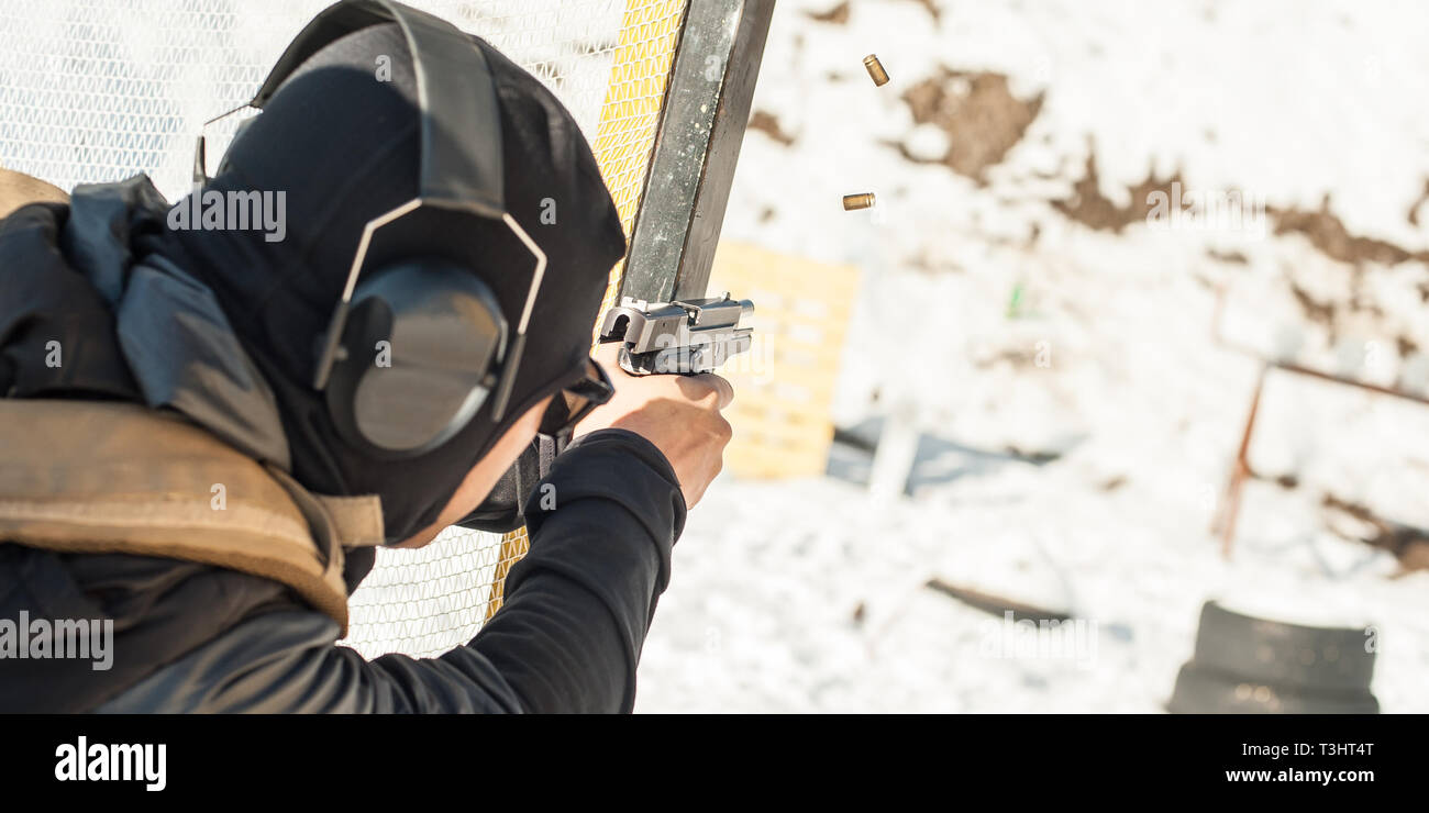 Detail back view of shooter holding gun in hand and shooting on target ...