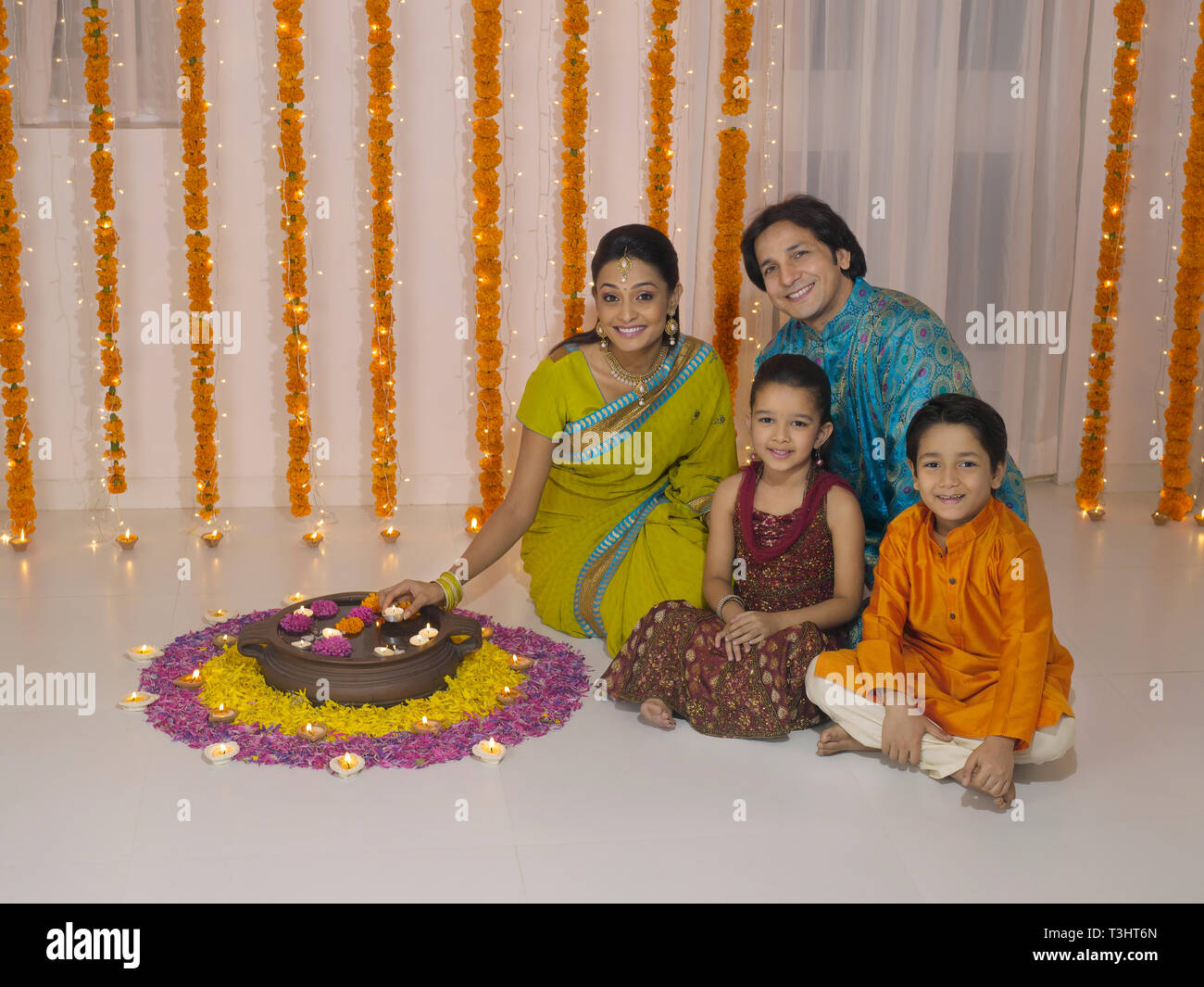 PORTRAIT OF AN INDIAN FAMILY OF FOUR CELEBRATING THE FESTIVAL OF DIWALI ...