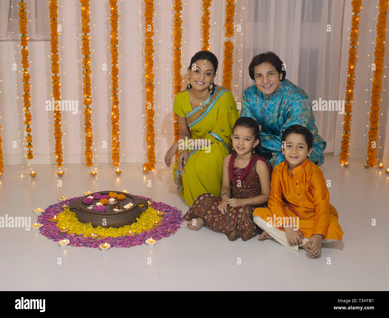PORTRAIT OF AN INDIAN FAMILY OF FOUR CELEBRATING THE FESTIVAL OF DIWALI ...