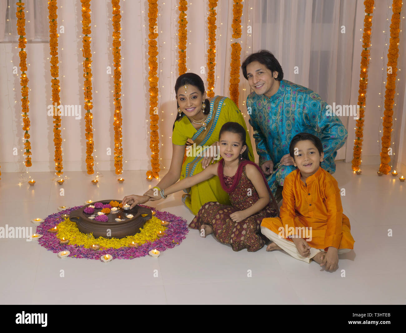 PORTRAIT OF AN INDIAN FAMILY OF FOUR CELEBRATING THE FESTIVAL OF DIWALI ...