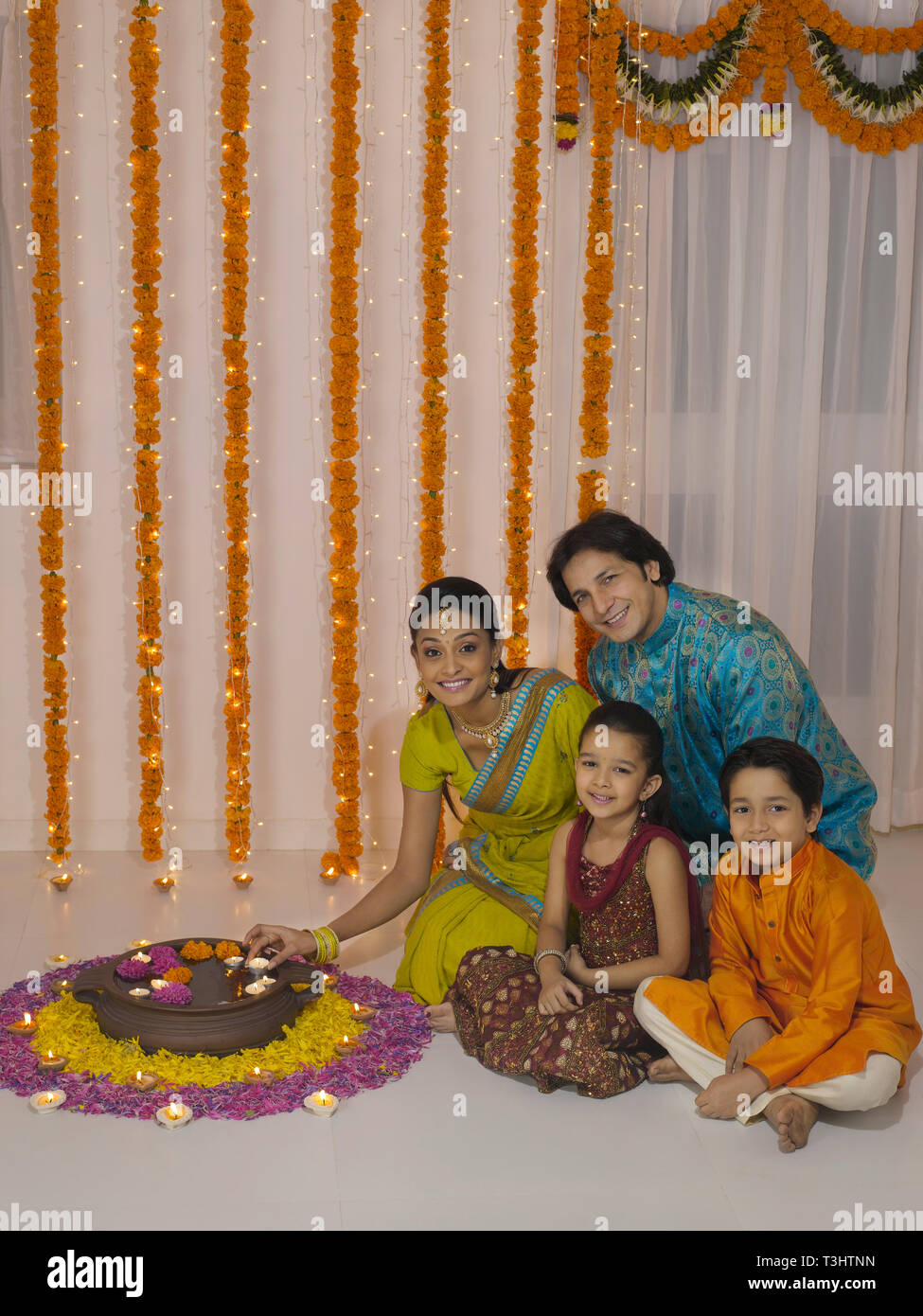 PORTRAIT OF AN INDIAN FAMILY OF FOUR CELEBRATING THE FESTIVAL OF DIWALI ...