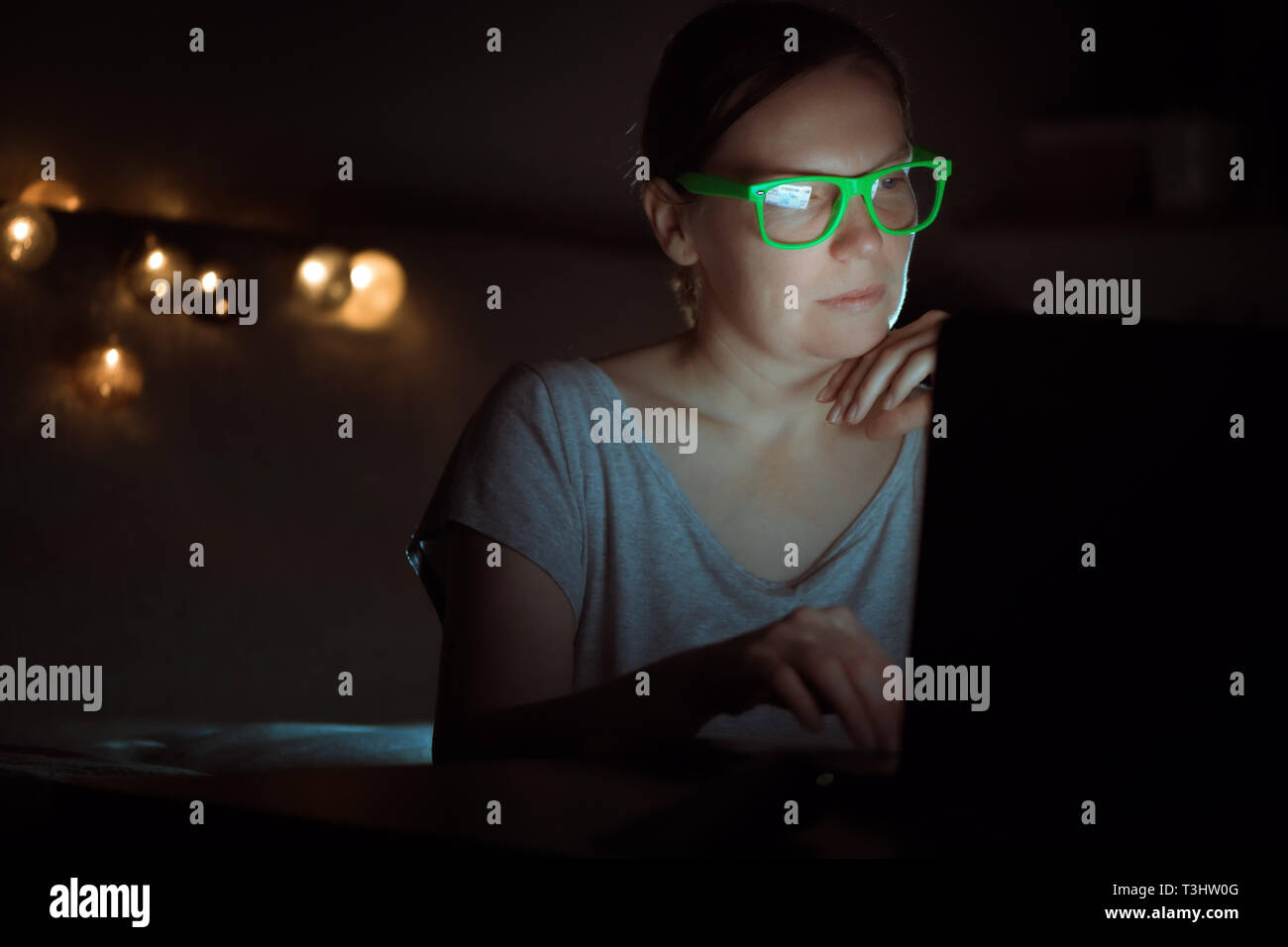 Low key portrait of busy woman working on laptop computer at night from ...