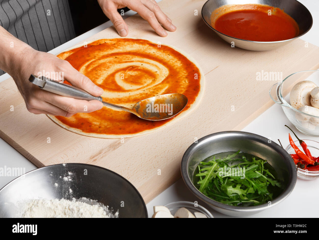 Process of pizza preparation. Chef spreading tomato sauce Stock Photo ...
