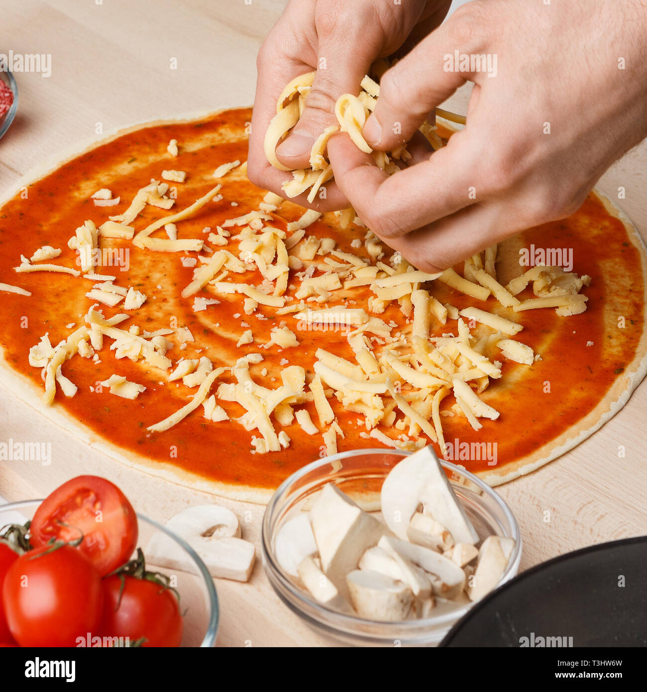 Pizzaiolo adding grated cheese to pizza base Stock Photo - Alamy