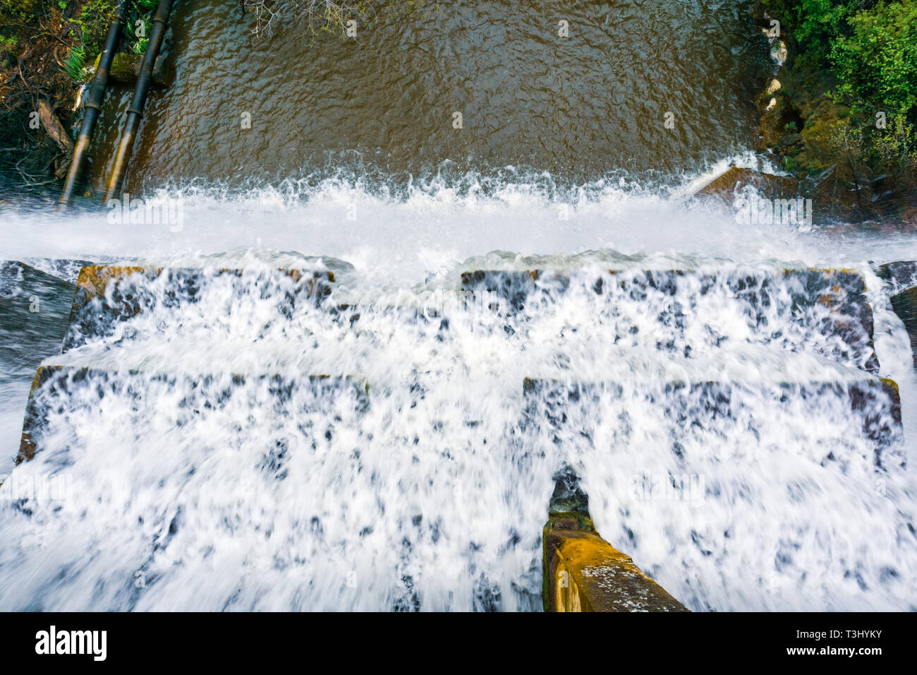 Looking down at the flow of water falling over a concrete dam, San ...