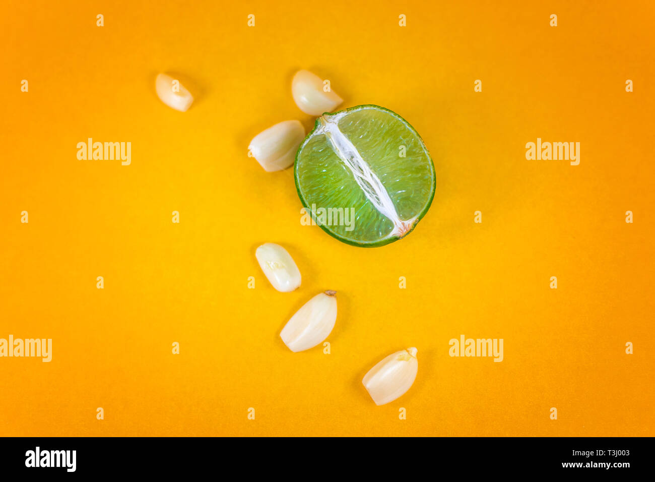 Top view of a slice of lemon surrounded by garlic cloves over a ...