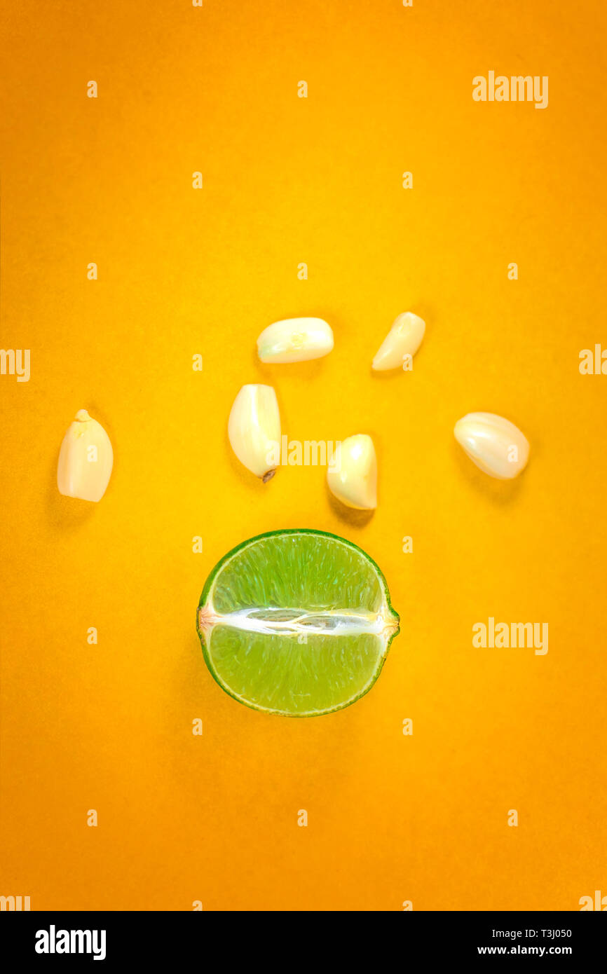 Graphic top view of a slice of lemon surrounded by garlic cloves over a ...